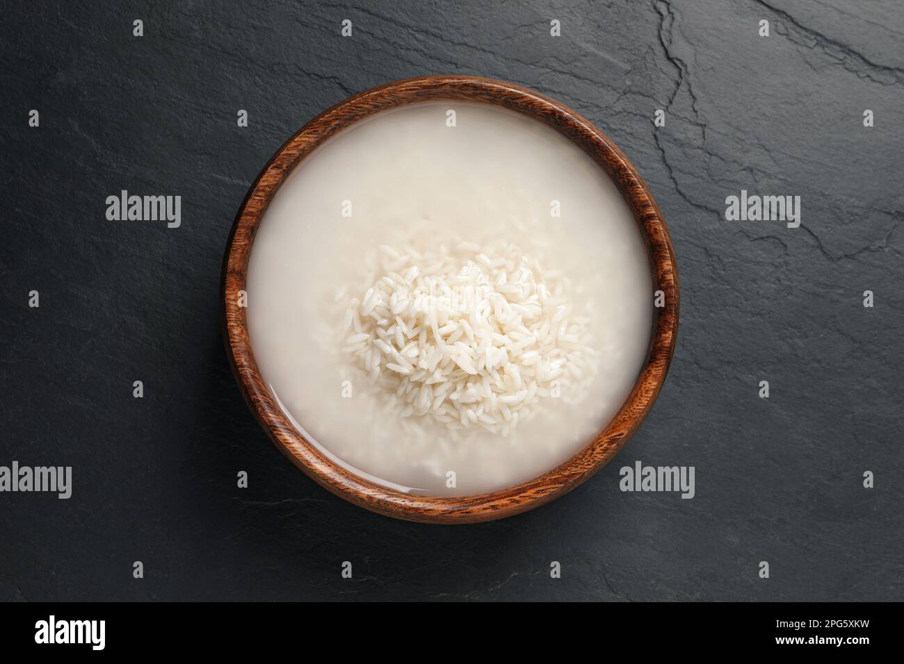 Rice soaked in water on black table, top view Stock Photo - Alamy