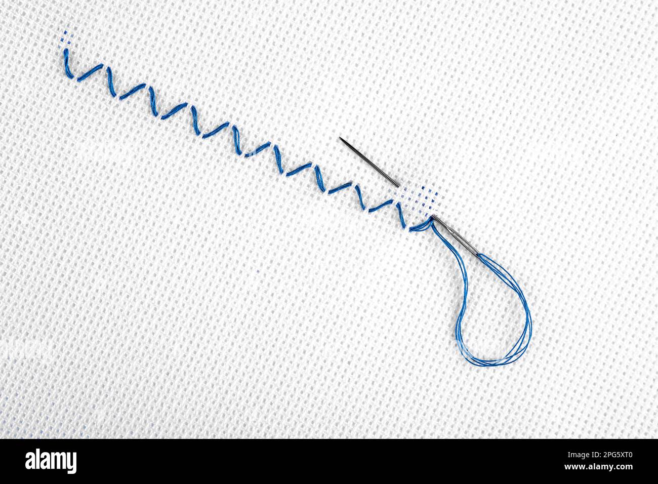 Embroidery stitches made with blue thread and needle on canvas, top ...