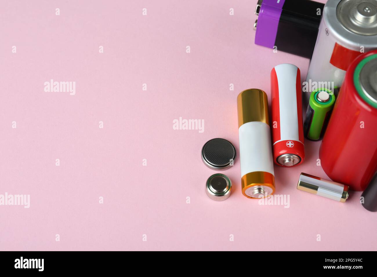 Different types of batteries on pink background, closeup. Space for ...