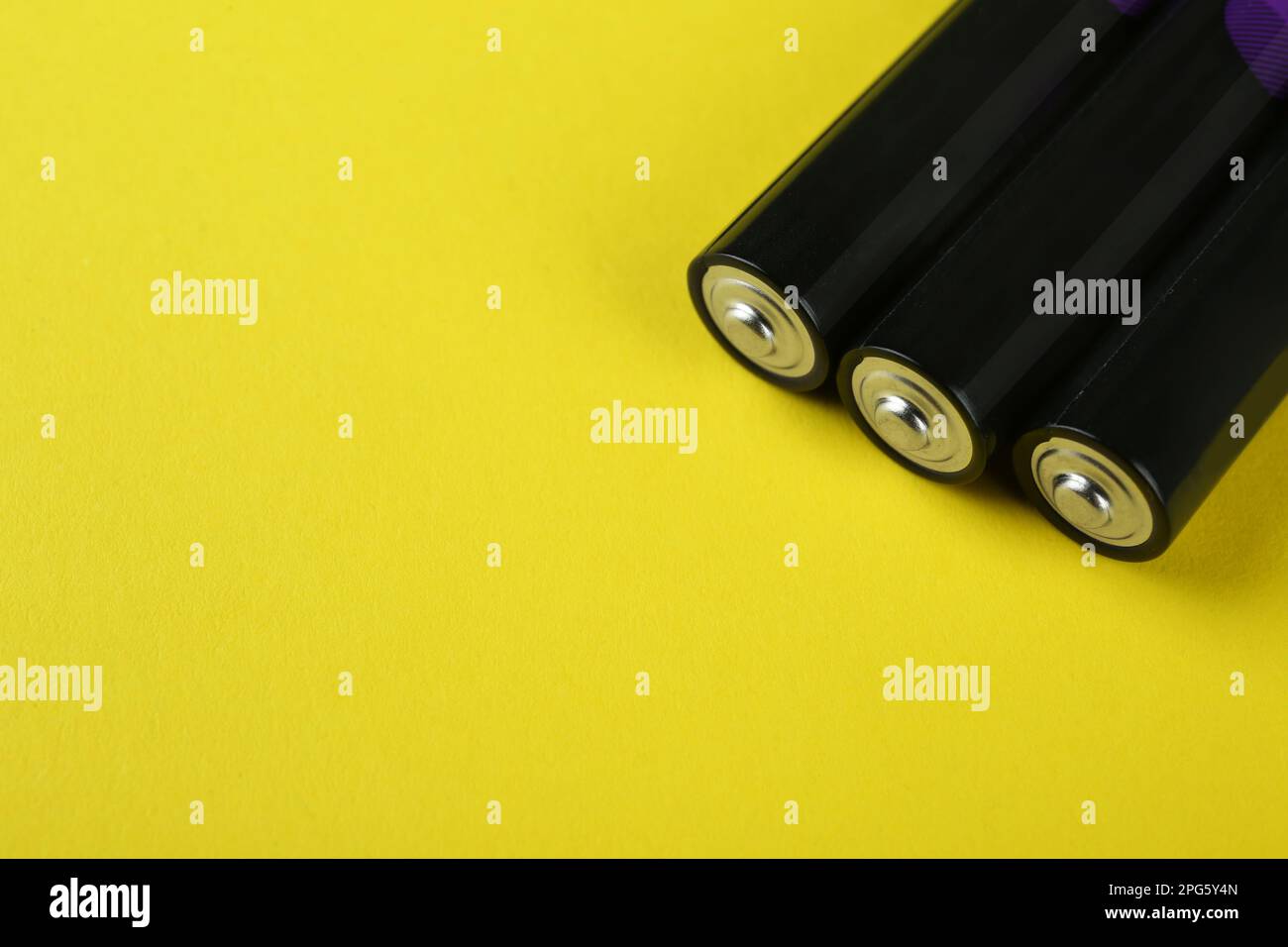 New AAA batteries on yellow background, closeup. Space for text Stock ...