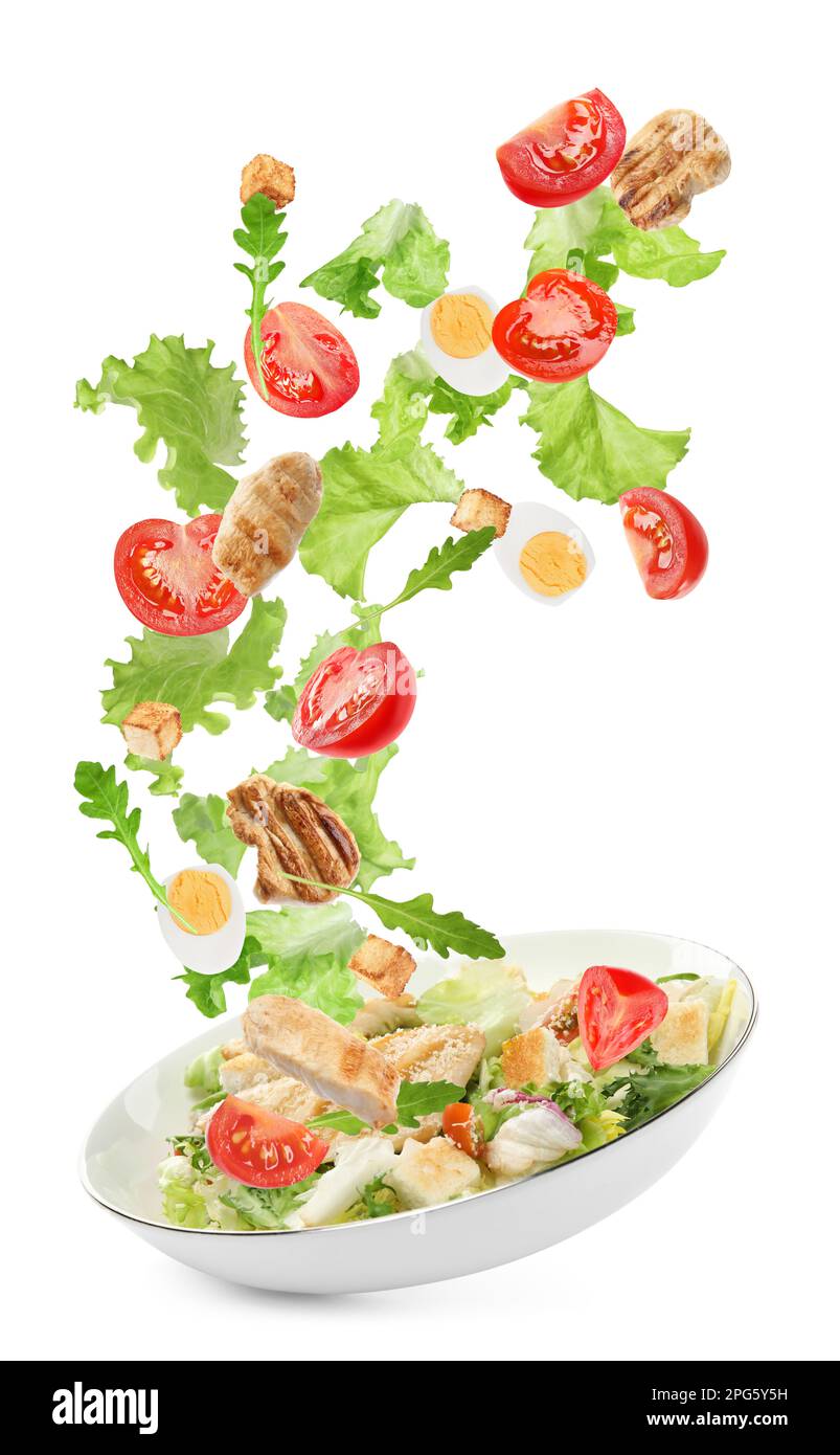 Tasty ingredients for Caesar salad falling into plate on white ...