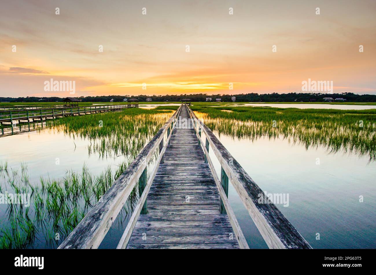 Coastal waters with a very long wooden boardwalk pier in the center ...