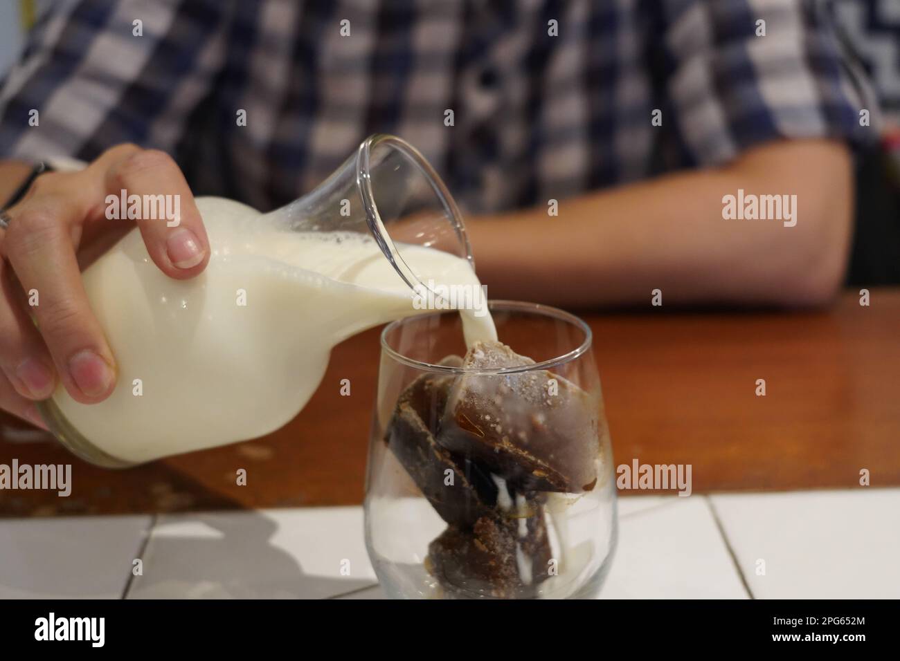 Milk Being Poured Into Glass Iced Coffee on the table in a cafe Stock ...