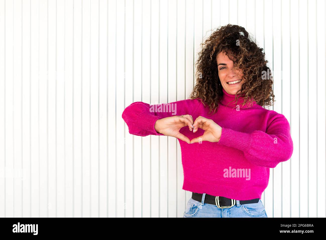 Happy adult female in warm pink sweater and jeans standing near striped ...