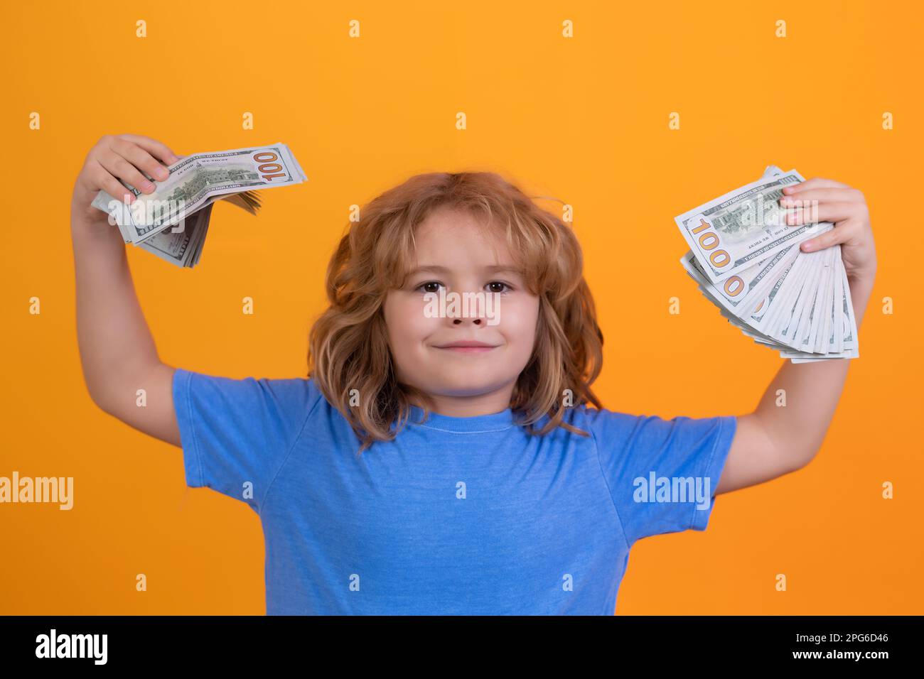 Child with lots of money dollar banknotes isolated over yellow studio ...
