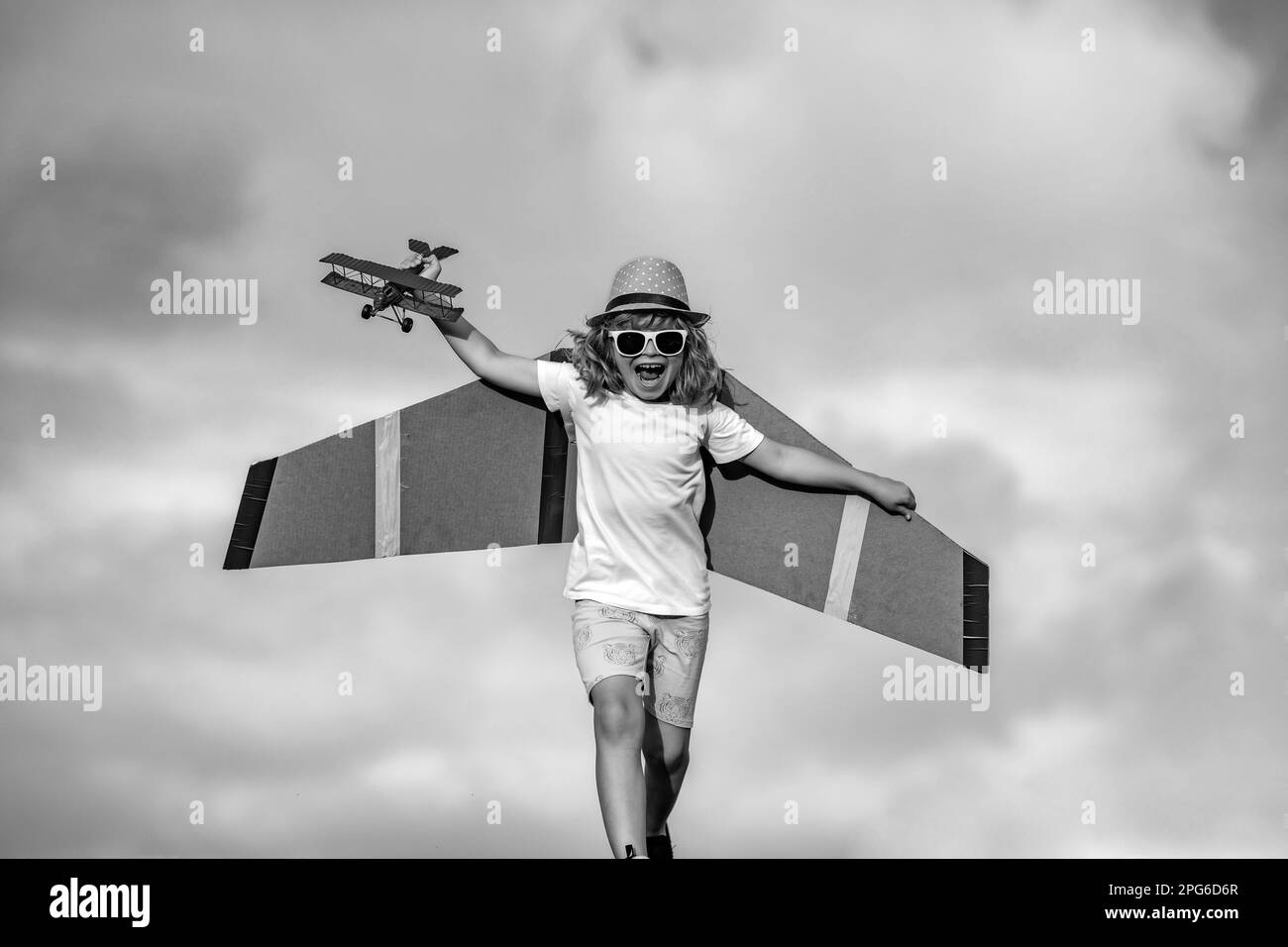 Little child boy is playing and dreaming of flying over the clouds ...