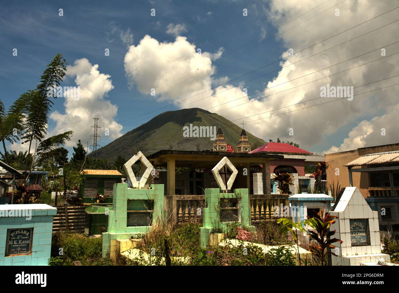 A rural cemetery in a background of Mount Lokon, an active volcano in ...