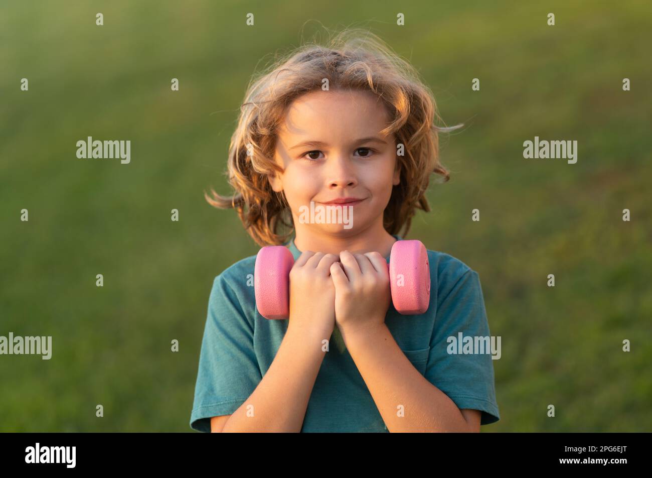Sport activities at leisure with children. Blonde boy holding dumbbells. Sports exercises for ...
