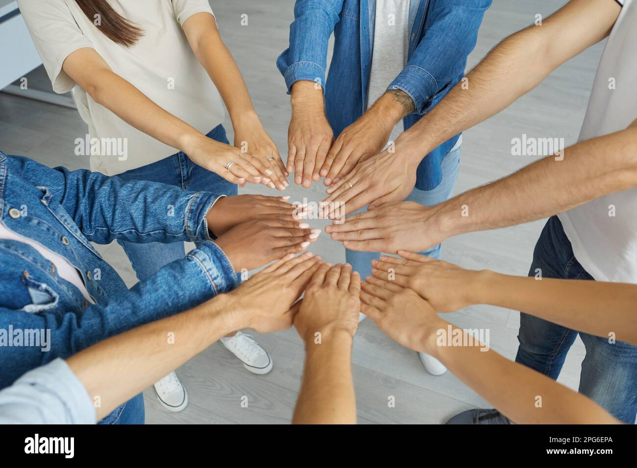 Team of diverse men and women joining hands to show concept of union ...