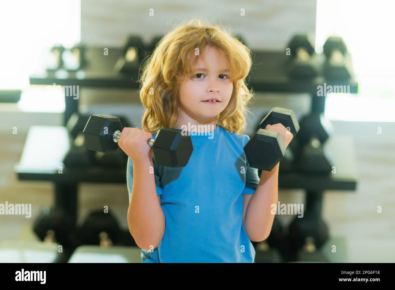 Kid raising a dumbbell. Cute child training with dumbbells. Kids ...