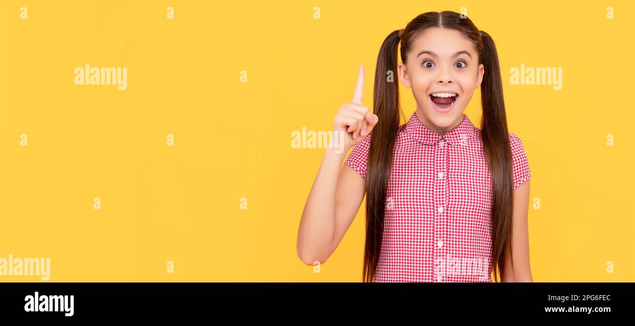 Happy girl child genius got idea pointing finger up yellow background ...