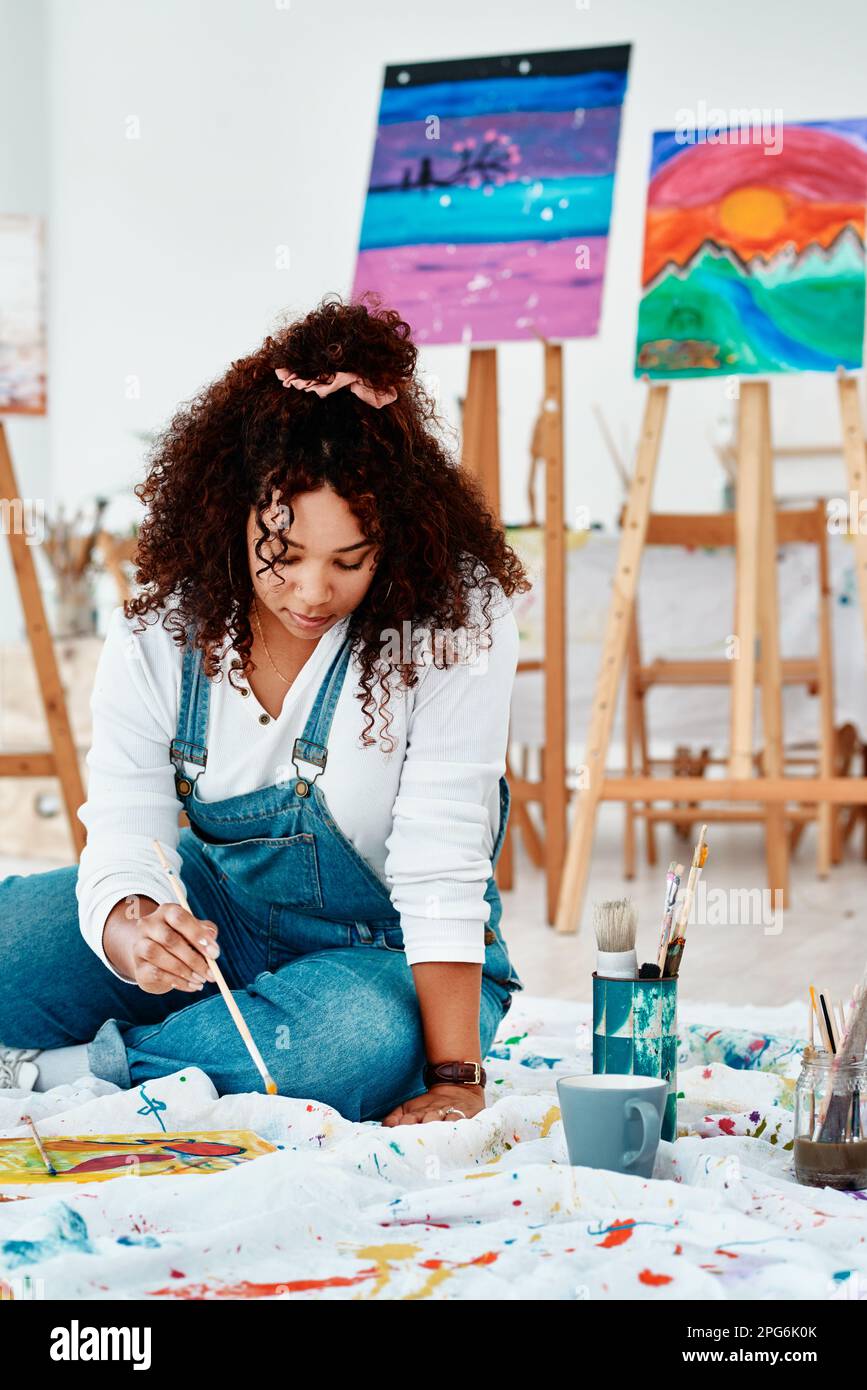 Lost in an artistic world. an attractive young artist sitting alone and ...