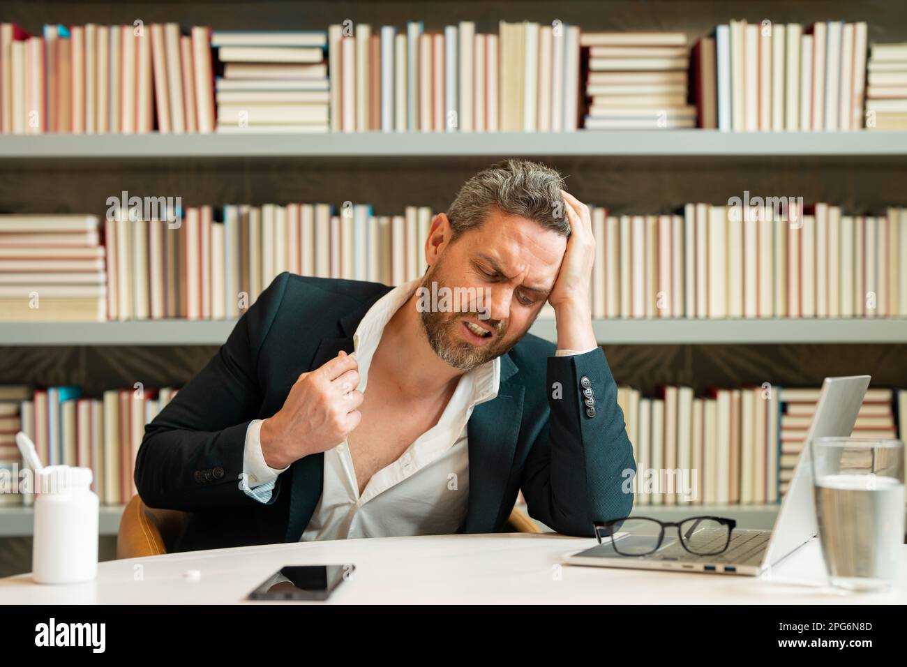 Headache, tiredness and stress. Business man in suit uses a laptop, is ...