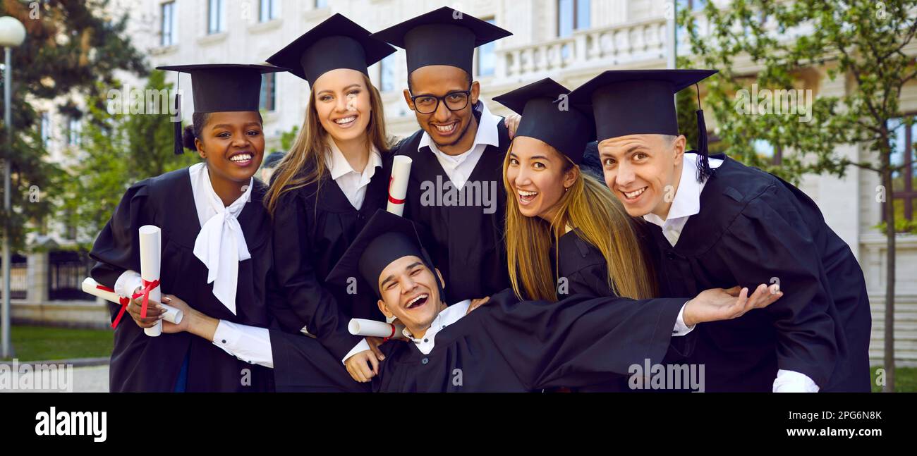 International smiling graduate people in gowns and caps posing after ...