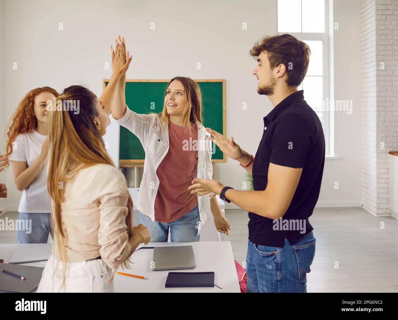 Students in class, two teen girls are giving five each other another ...