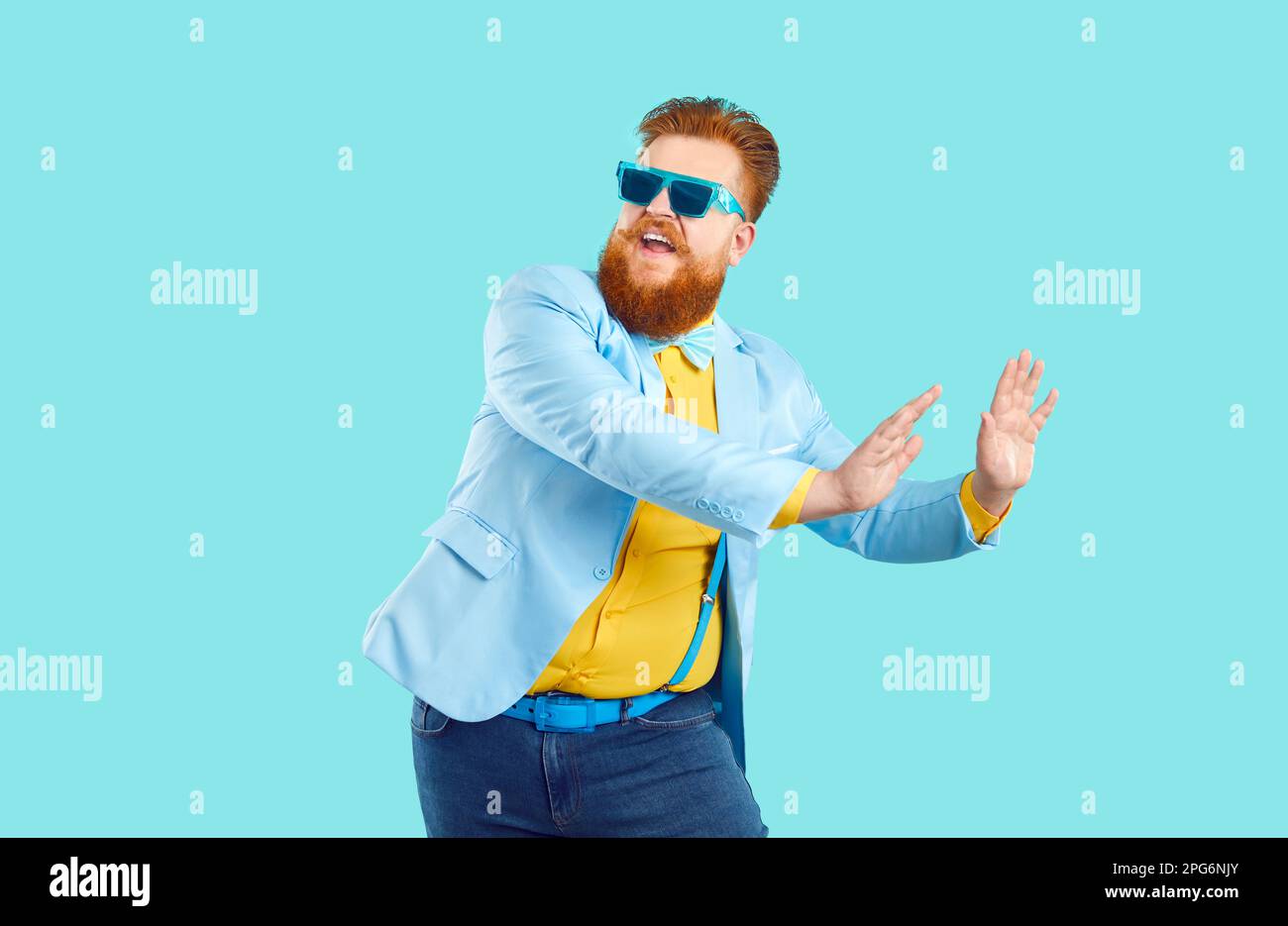 Funny happy chubby man in funky party outfit dancing on turquoise color ...
