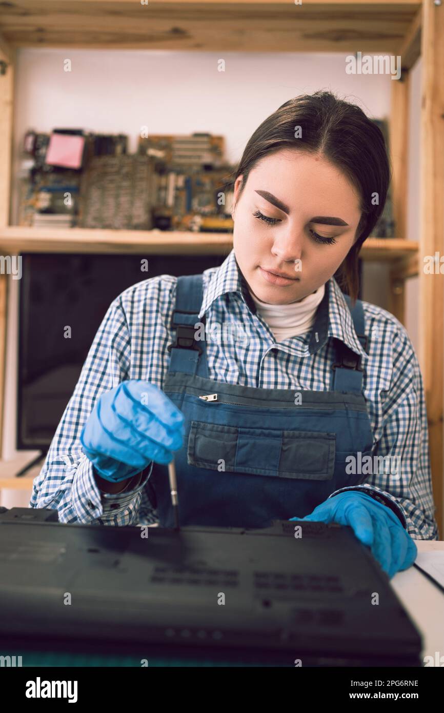 Computer repair shop. Engineer performing laptop maintenance unscrew ...