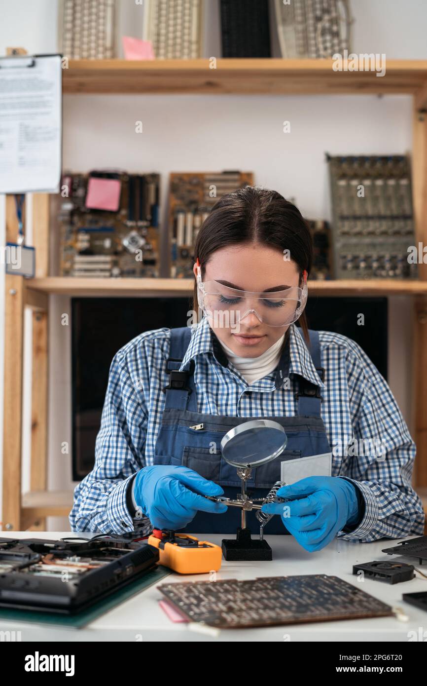 Technician repairing the laptop motherboard in the lab examines small ...