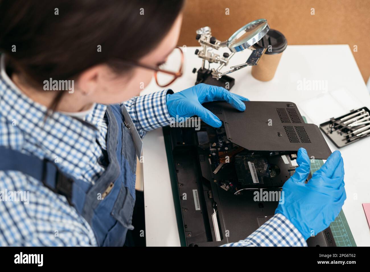 Laptop disassembling at electronic repair shop. Female engineer ...