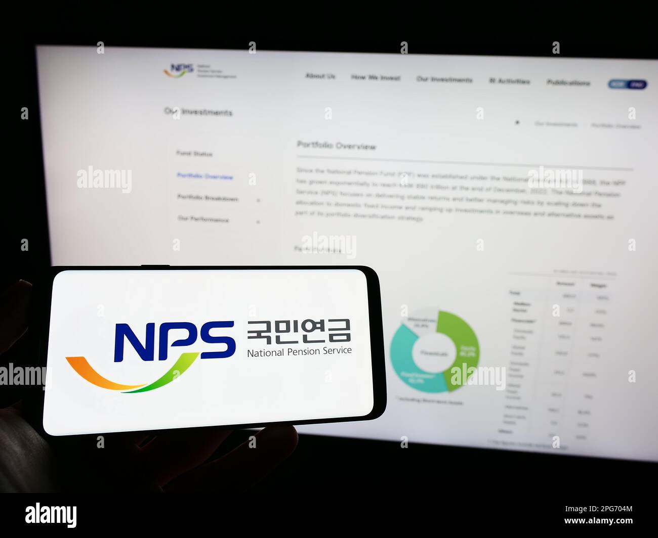 Person holding mobile phone with logo of National Pension Service of Korea (NPS) on screen in ...