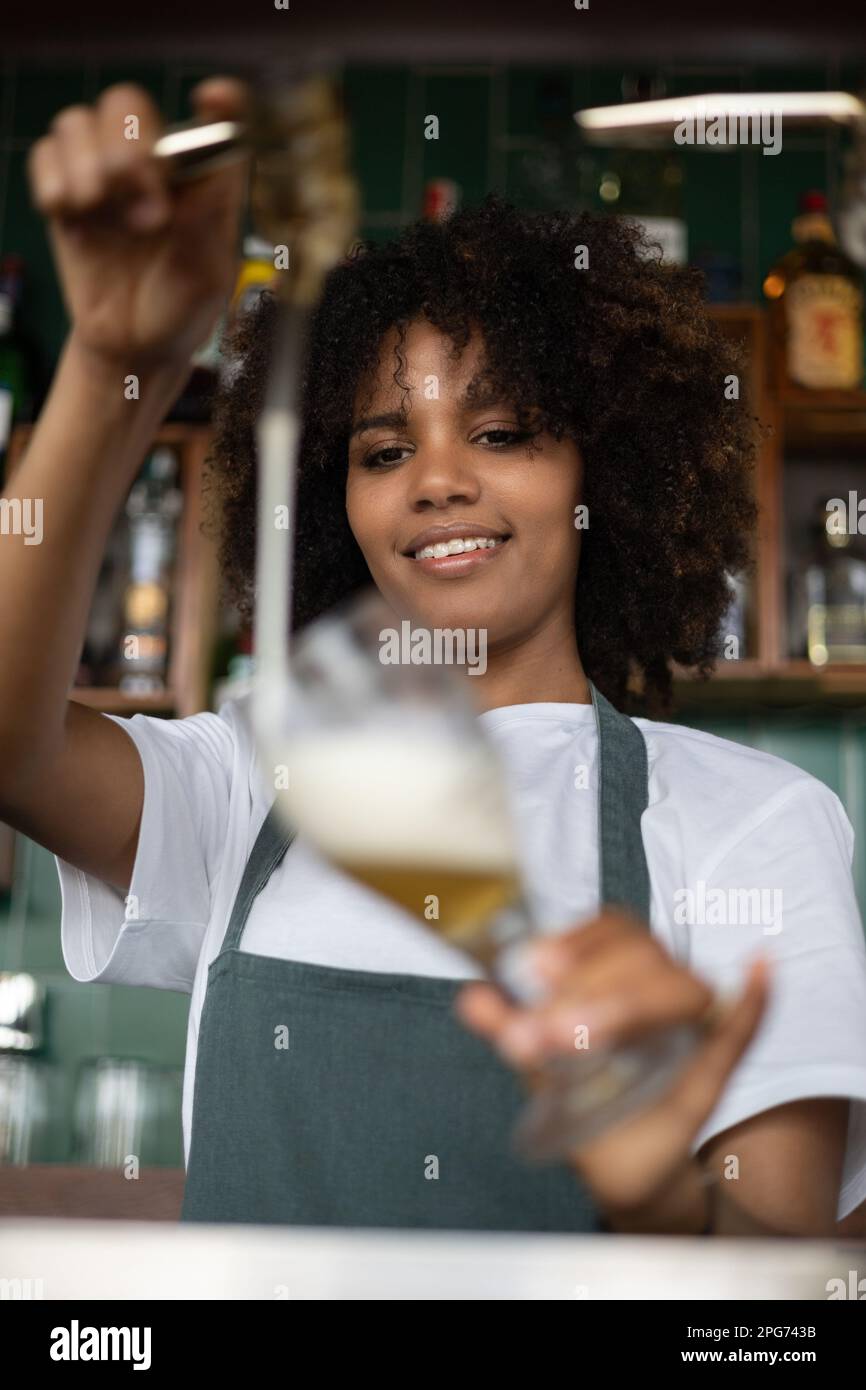 Beautiful African waitress woman serving beer Stock Photo - Alamy