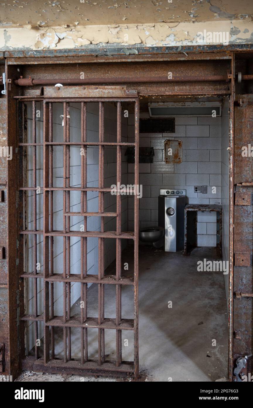This image depicts a prison cell featuring a barred door leading into ...