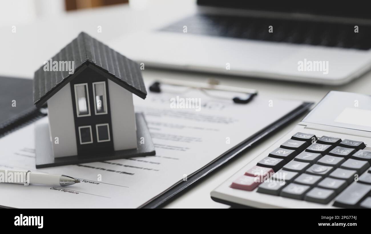 Model house put on contract documents with calculator and laptop ...