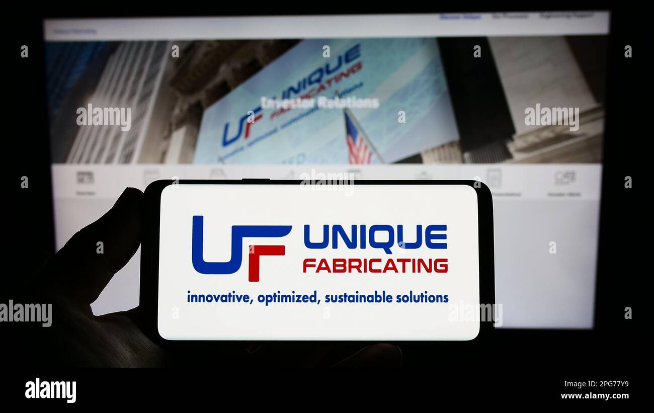 Person holding smartphone with logo of US manufacturing company Unique ...