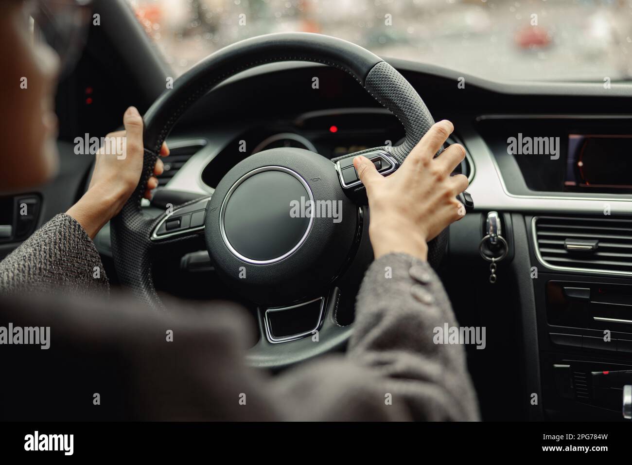 Back view of woman driver pushes the button on steering wheel during ...