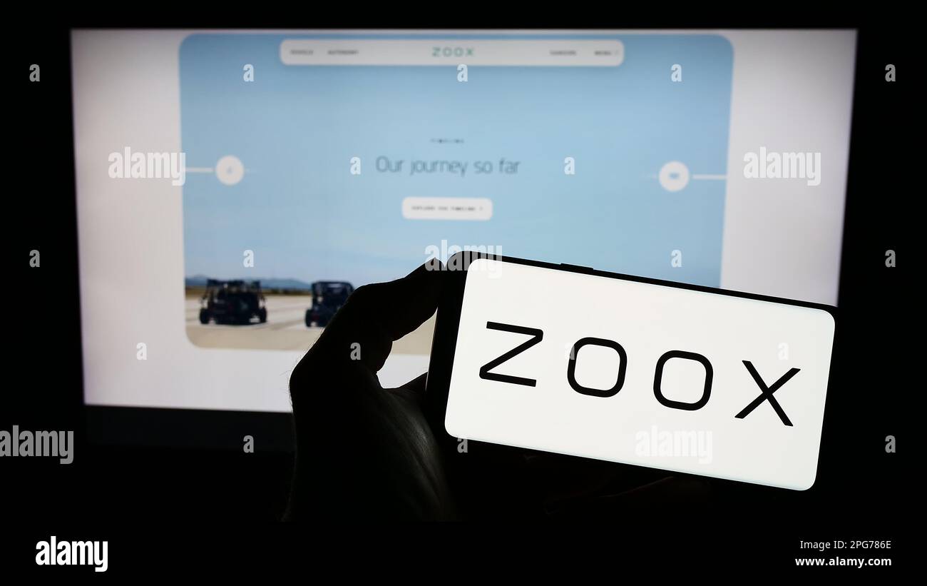 Person holding cellphone with logo of US autonomous vehicle company ...