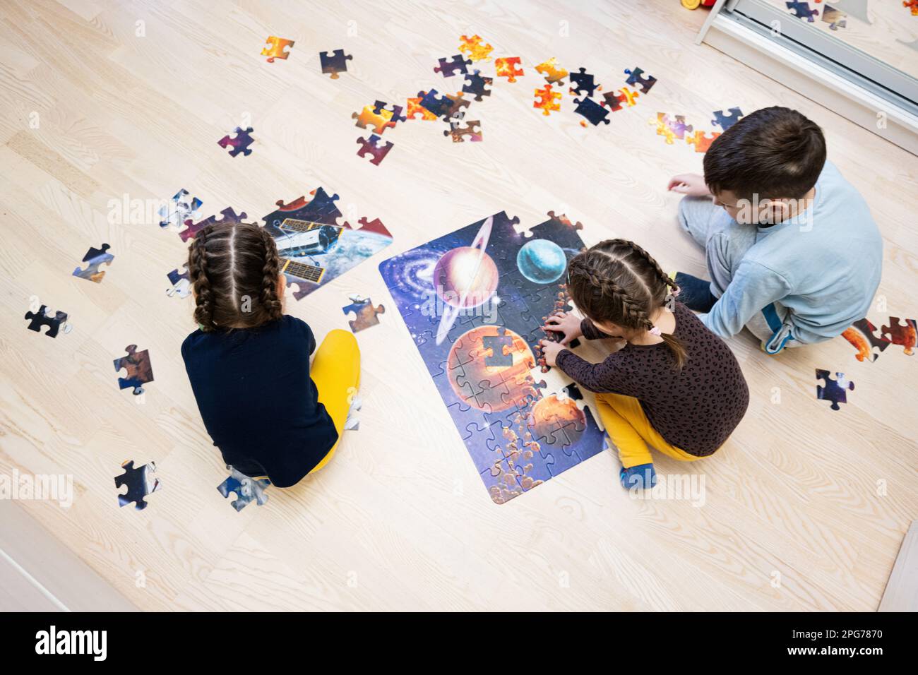 Children connecting jigsaw puzzle pieces in a kids room on floor at ...