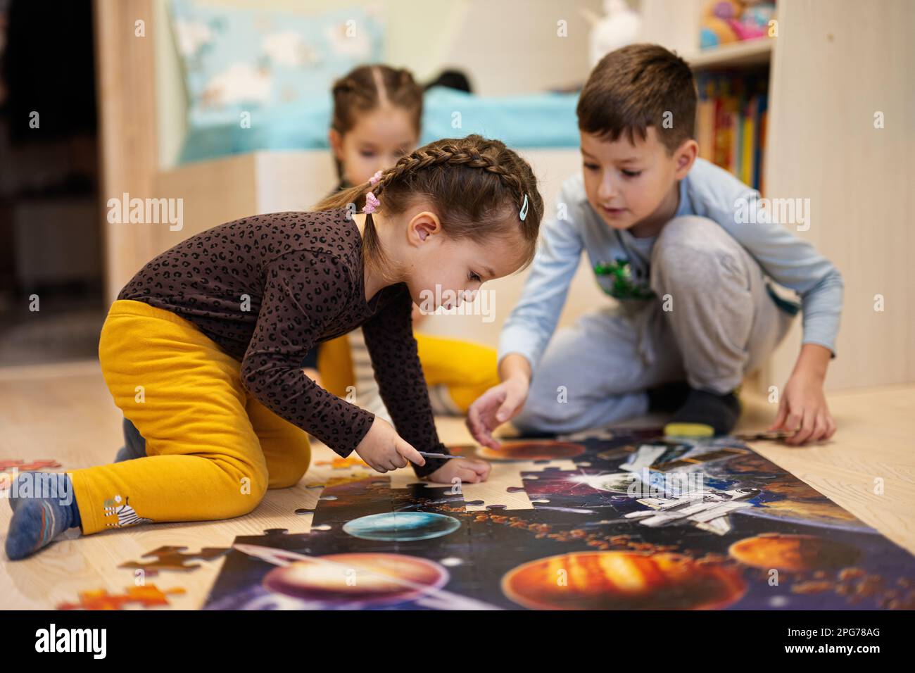 Children connecting jigsaw puzzle pieces in a kids room on floor at ...
