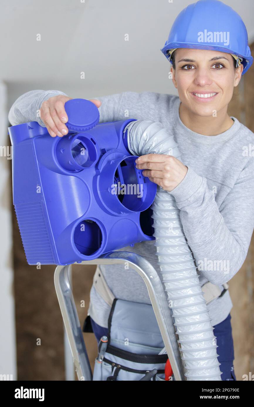 female worker fitting air conditions pipe in building ceiling Stock ...