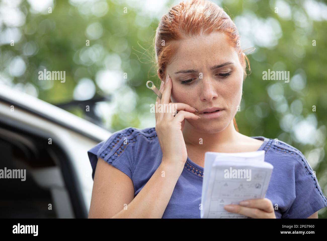 female motorist holding spanner and reading instructions Stock Photo ...