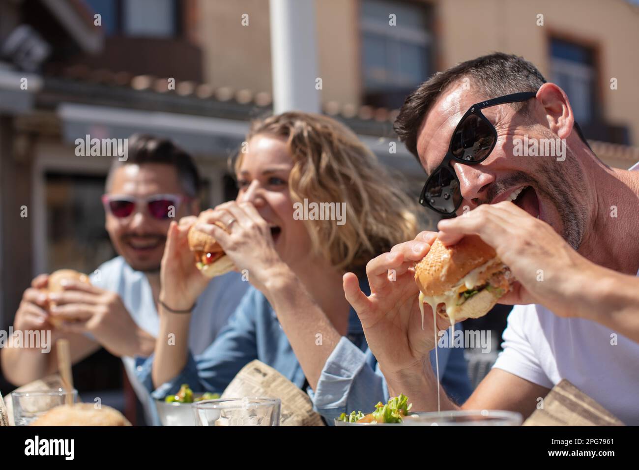 happy friends are eating burgers and smiling Stock Photo - Alamy
