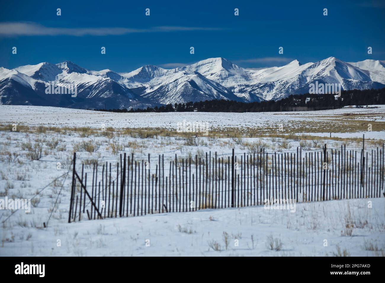 A landscape of a field surrounded by fences and snowy mountains in ...