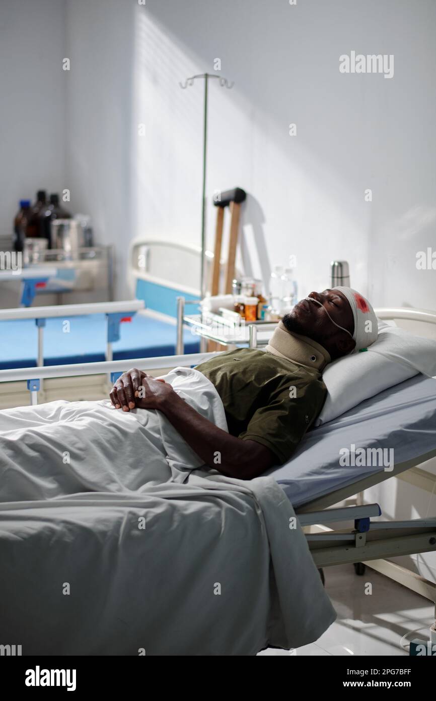 Vertical image of wounded man lying unconscious in bed in hospital ...