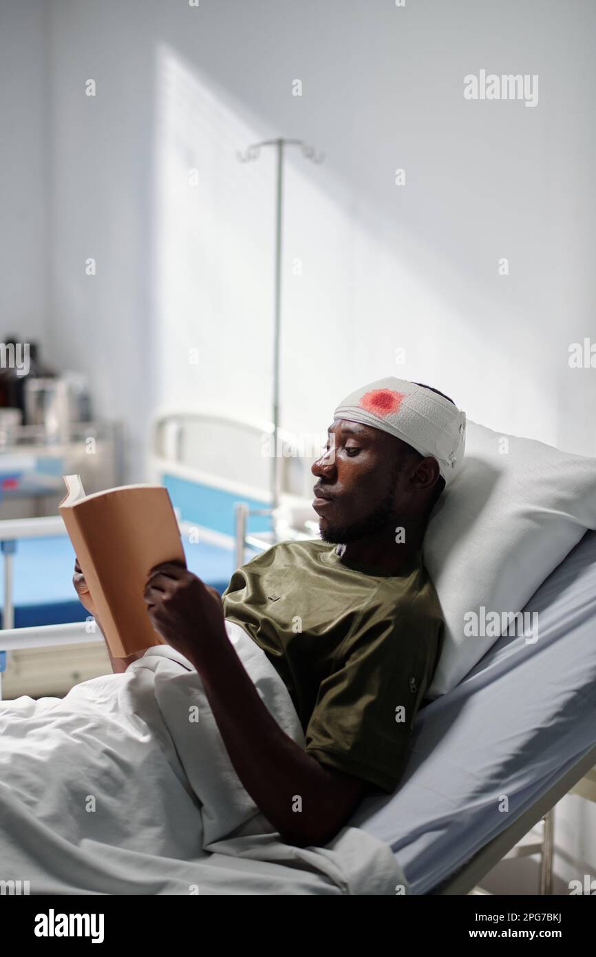 African American wounded soldier lying on bed and reading a book in ...