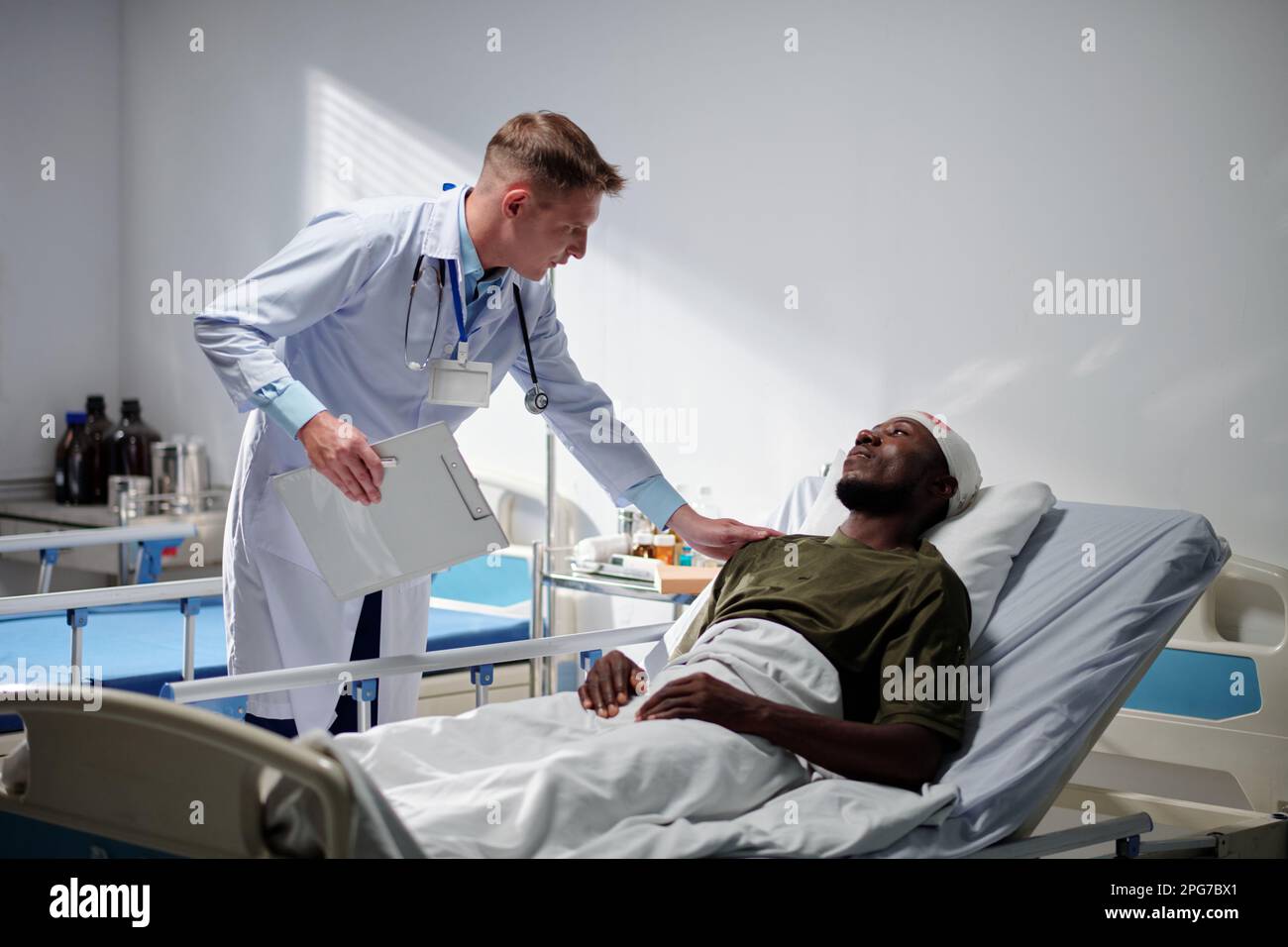 Doctor asking about health condition to soldier while he lying on bed ...