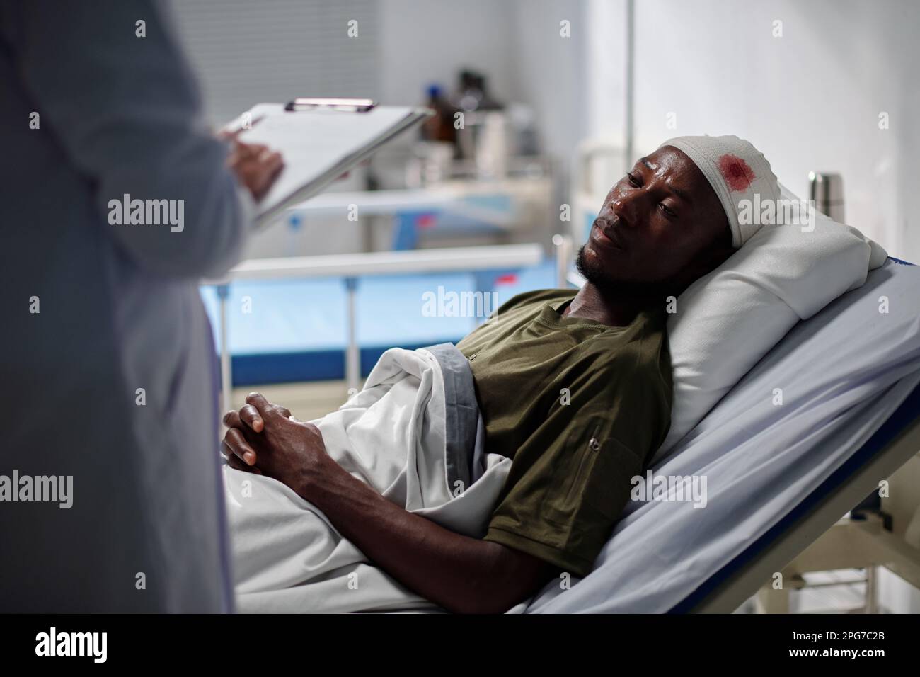 African American patient with injured head talking to doctor while he ...