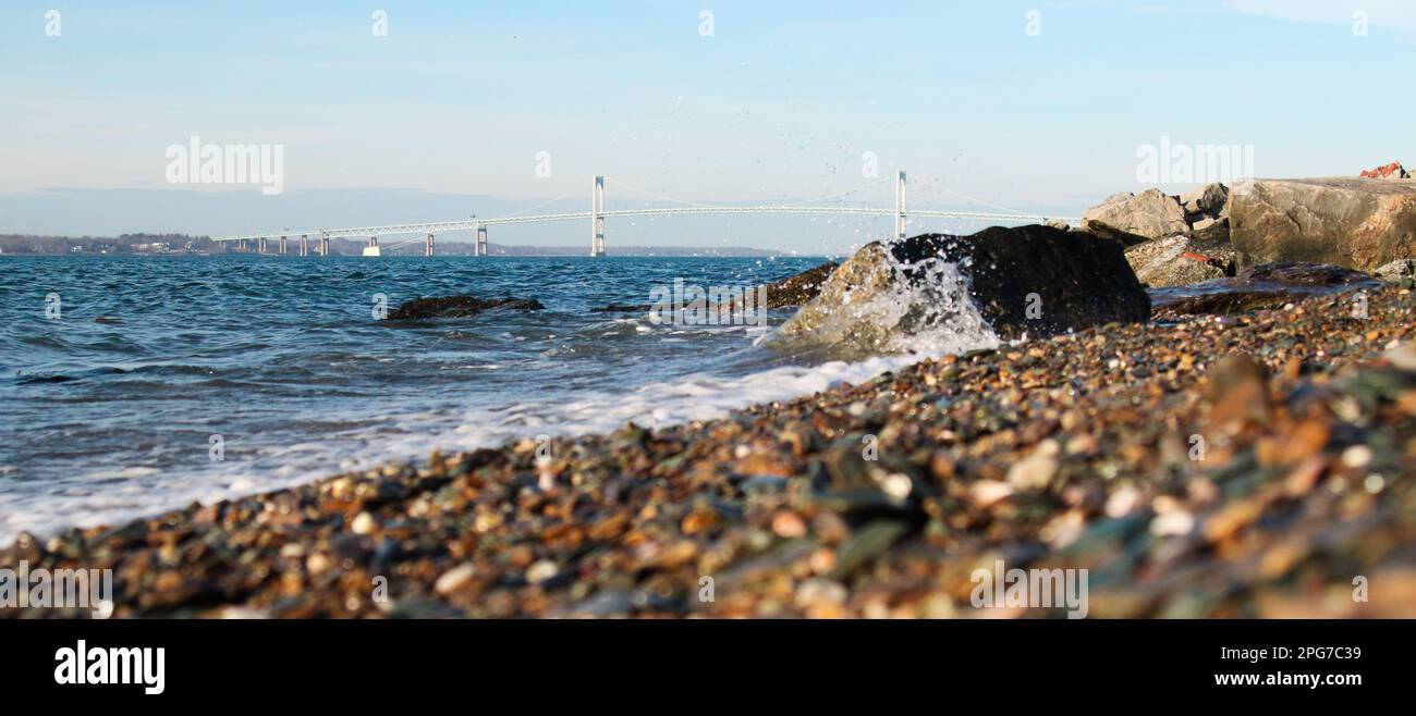 Waves crashing up against a large rock on a rocky seashore. Blue ocean ...