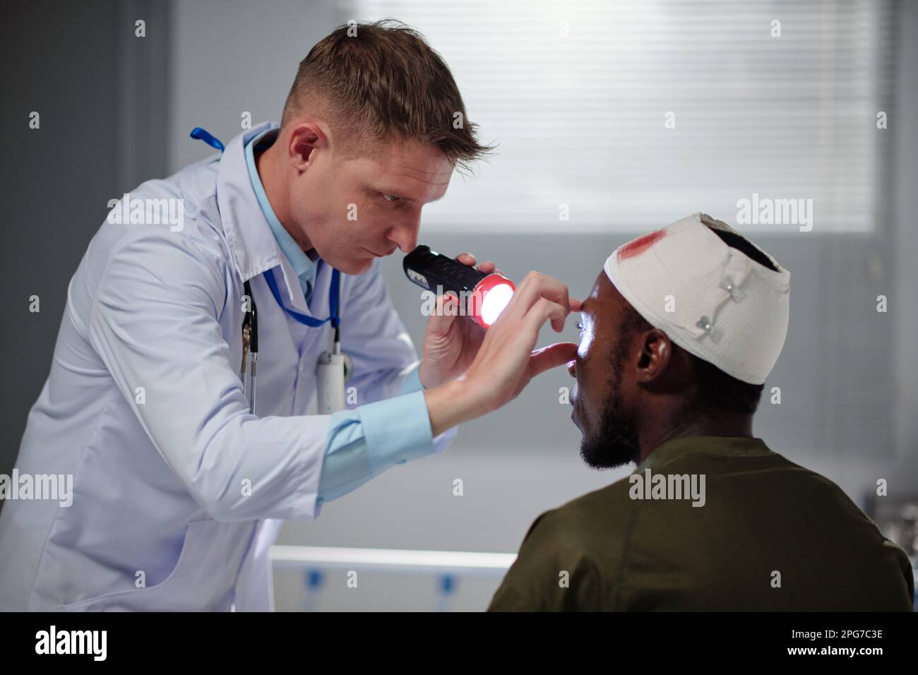 Professional doctor in white coat examining injured soldier during ...
