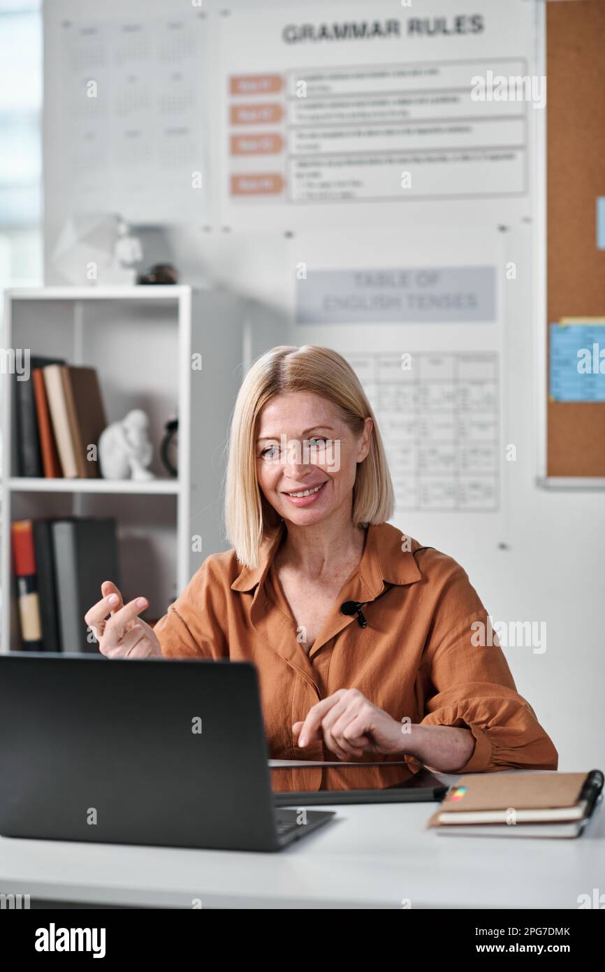 Vertical image of teacher having online lesson with students while ...