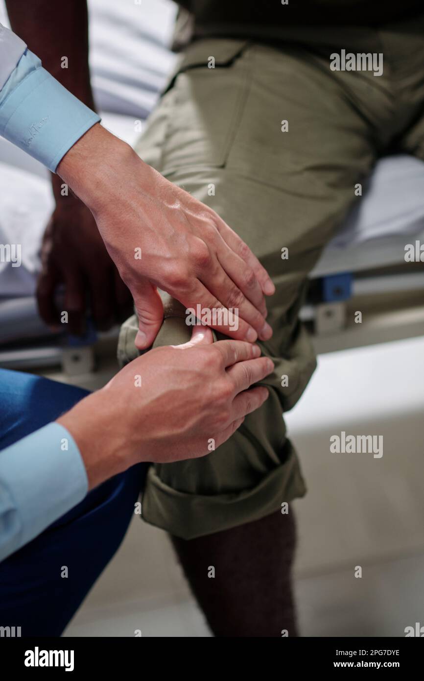 Vertical image of doctor examining the leg of soldier during his visit ...