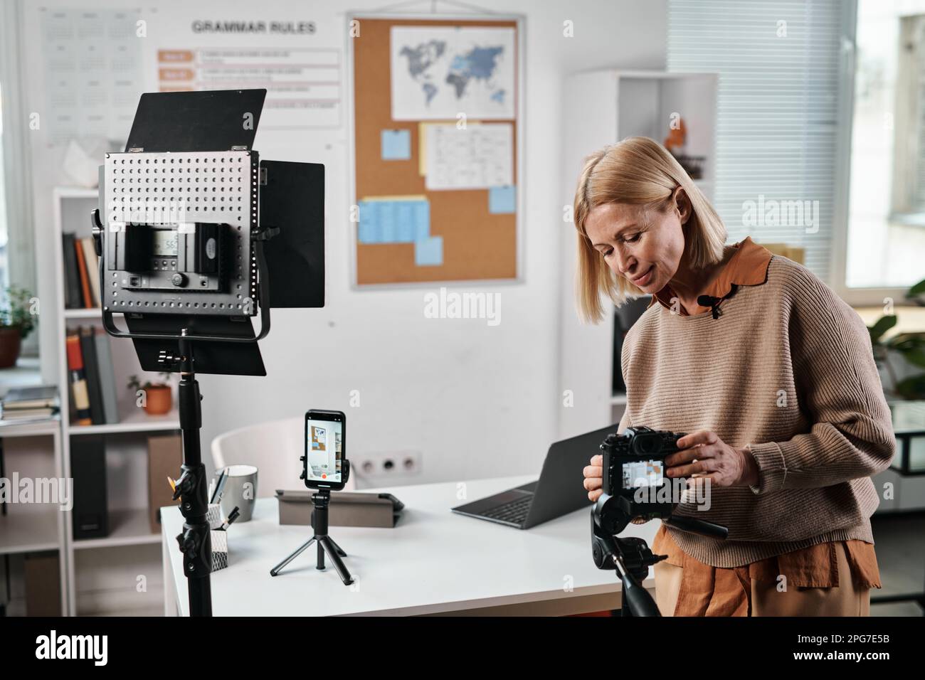 Mature teacher using professional camera and smartphone for recording ...