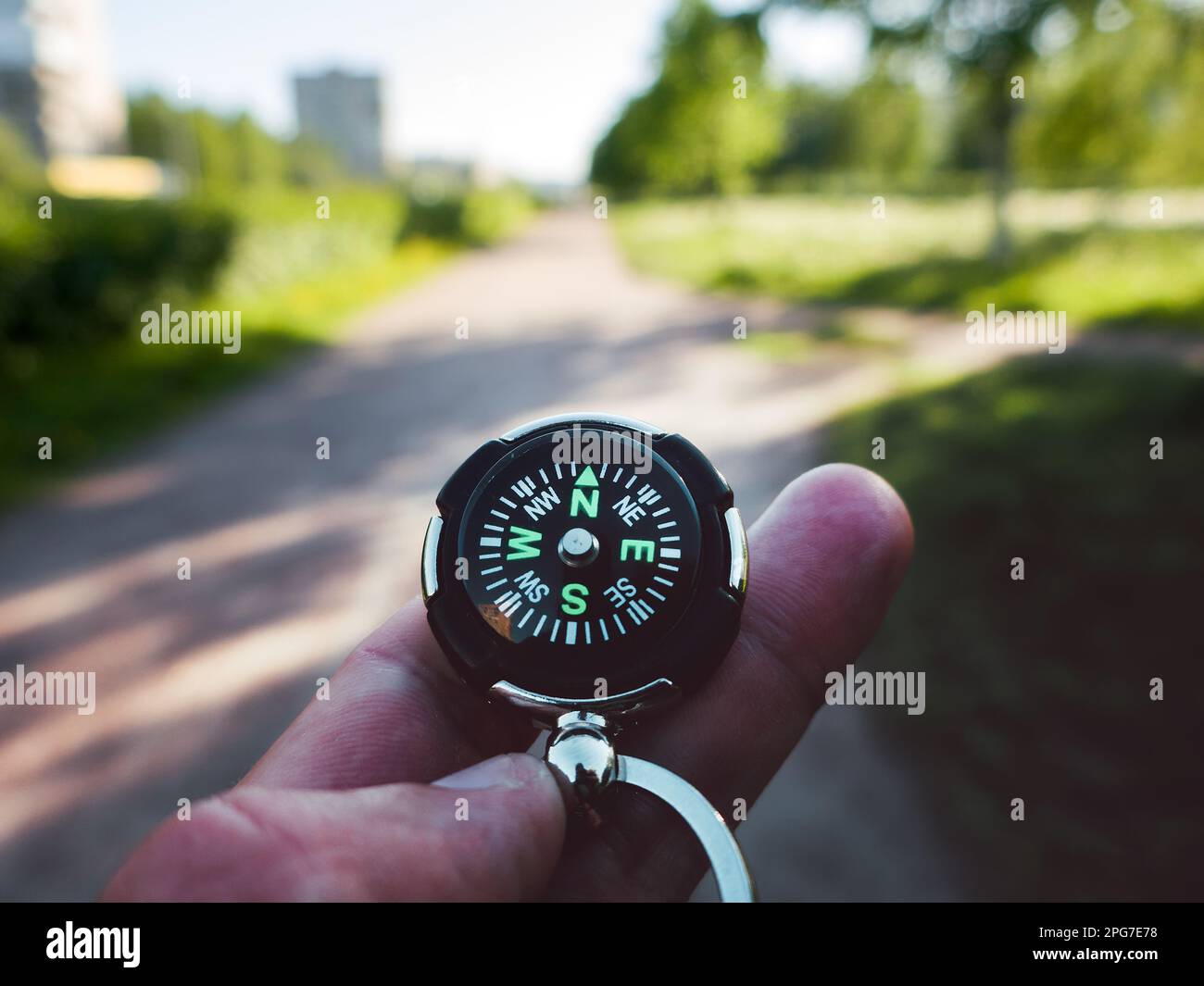 A compass in person's hand in park. Orient yourself in current ...