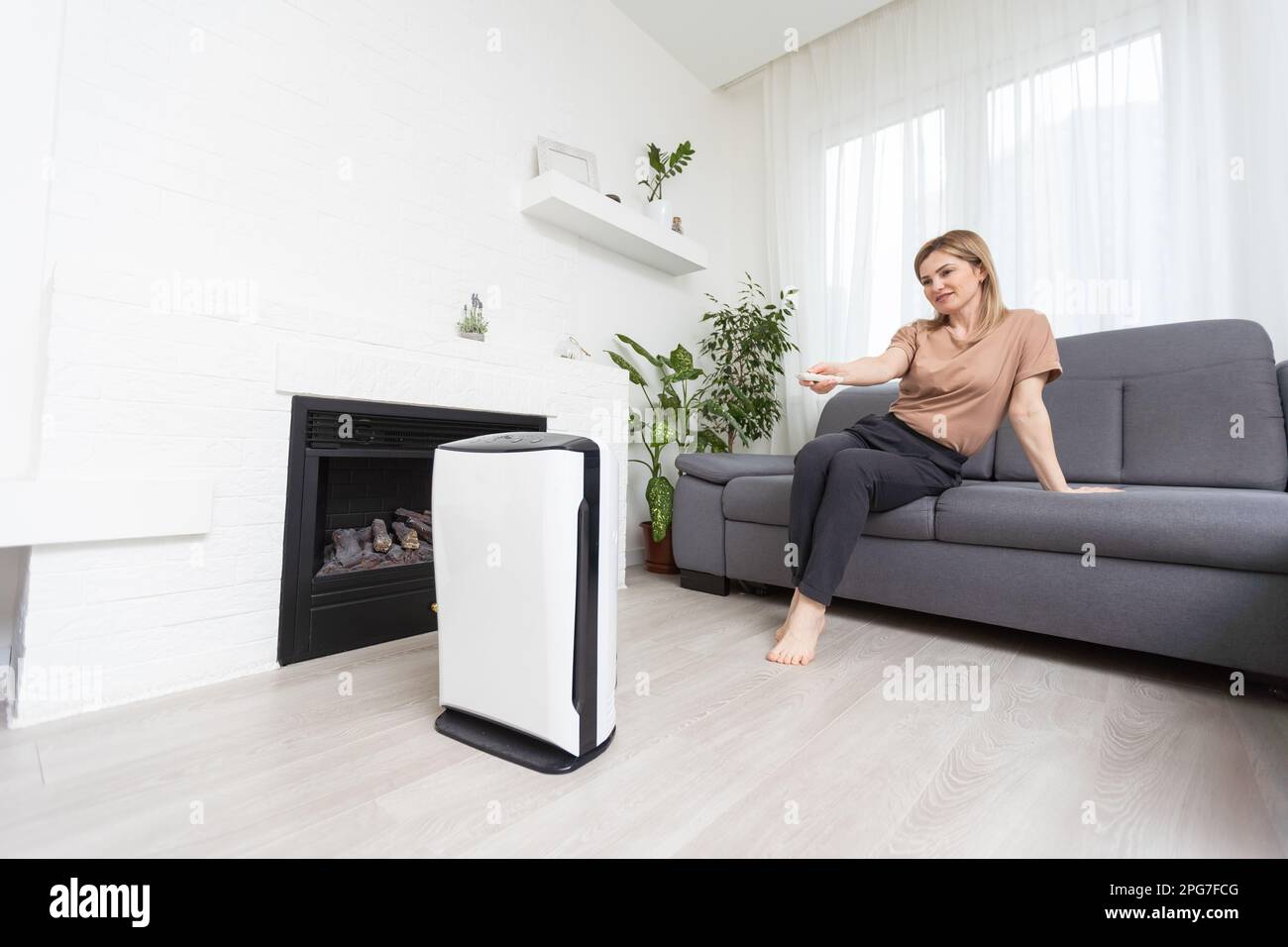 Woman using air purifier, dust filter, clean and health air Stock Photo ...