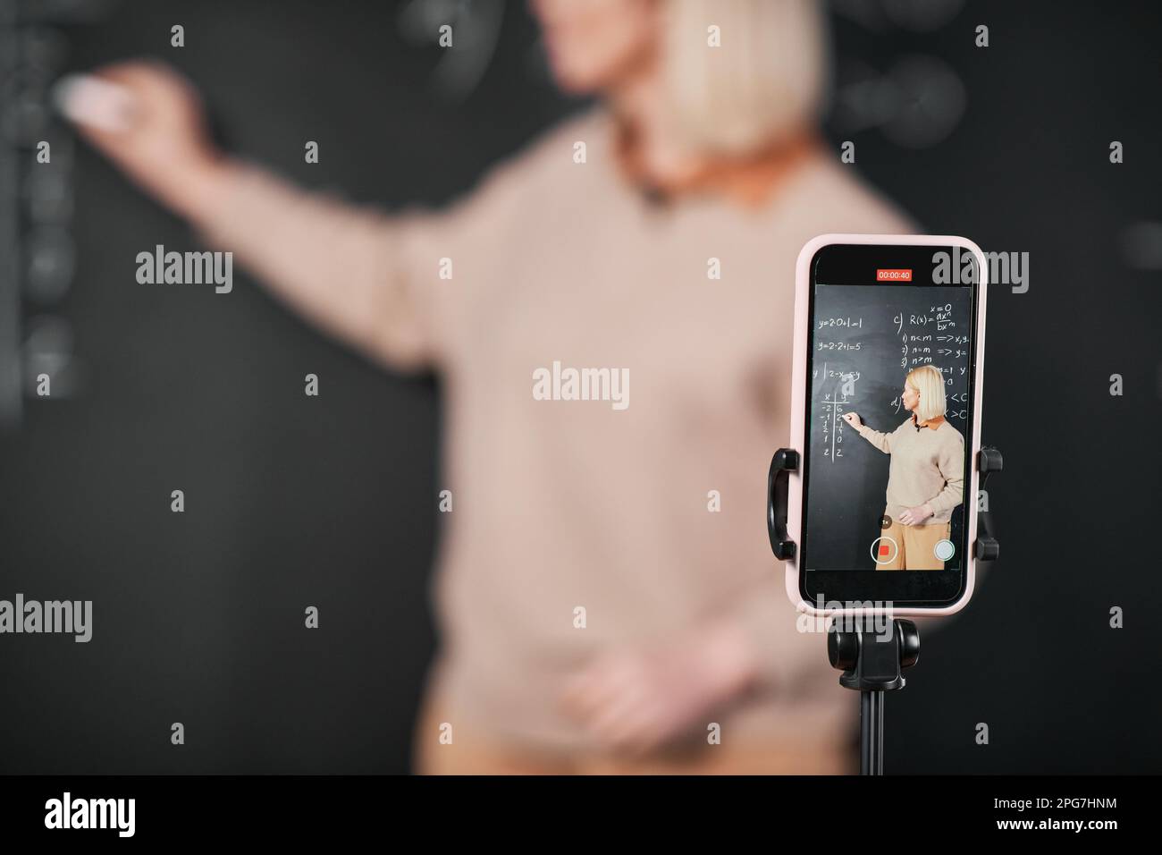 Teacher recording lesson on smartphone in class, she standing near the ...