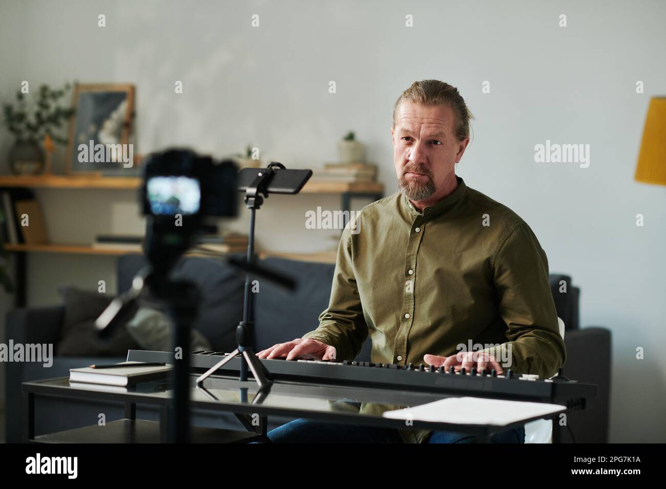Music teacher using camera for online lesson while playing piano at ...