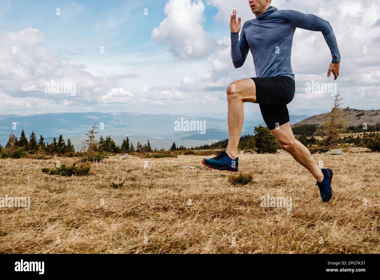 male athlete runner cross country running on mountain trail, blue long ...
